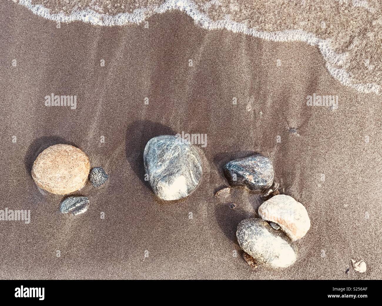 Stones on sand on the edge of Lake Maggiore with the water from the ...