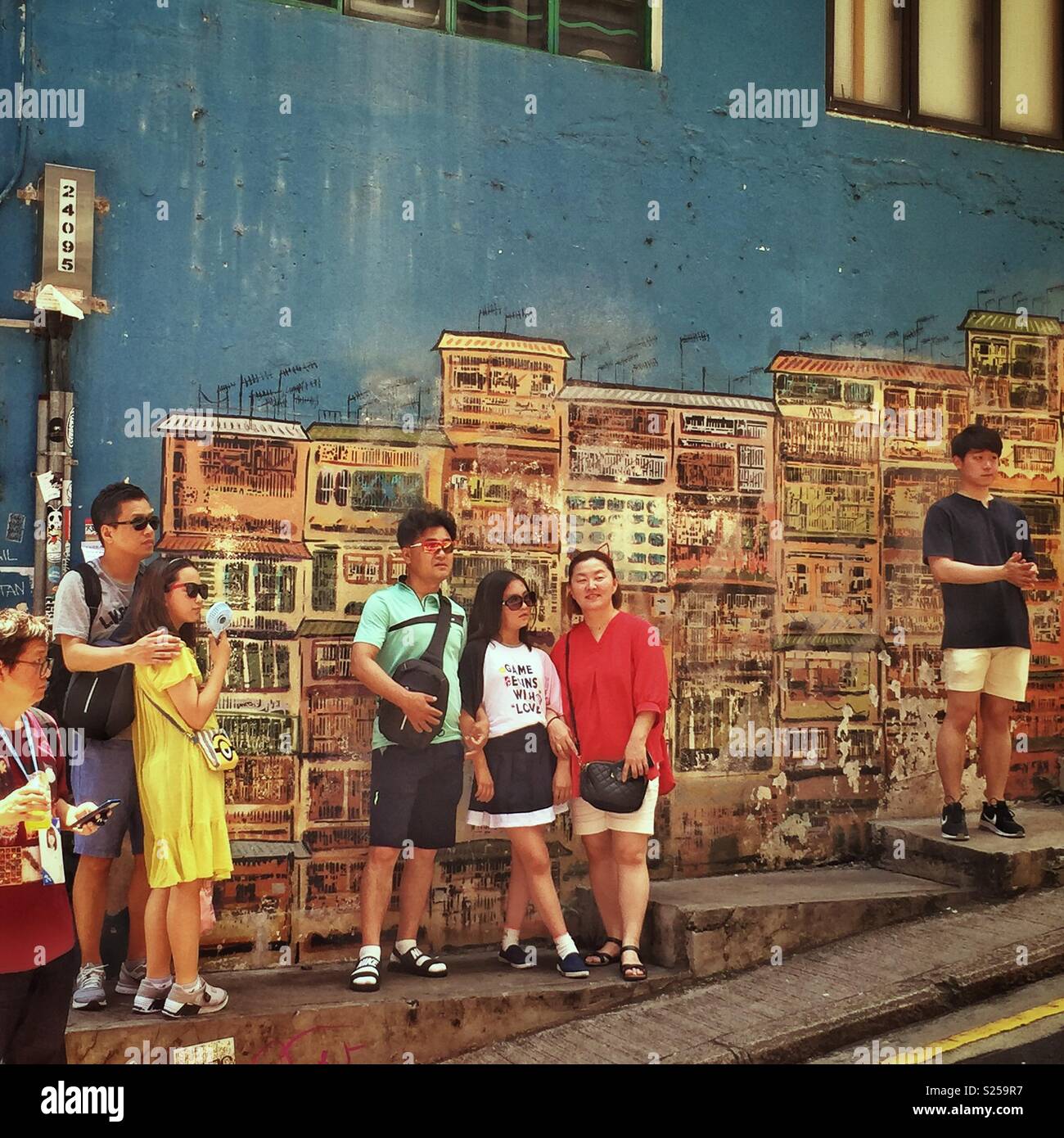 Mainland Chinese tourists pose for photographs in front of a mural by ...