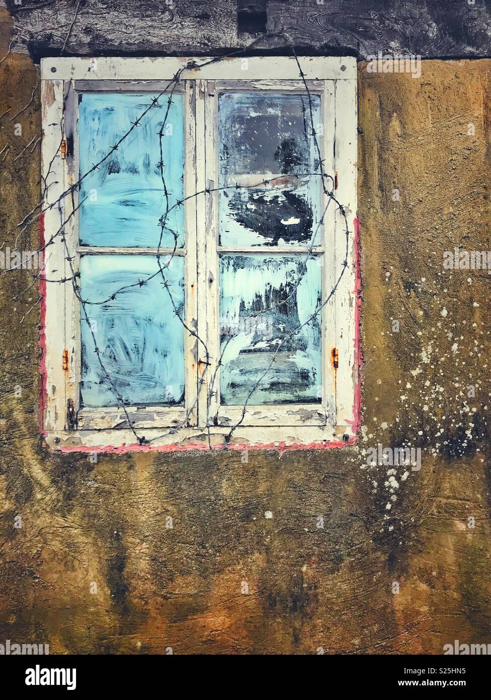A beaten up window with barbed wire Stock Photo - Alamy