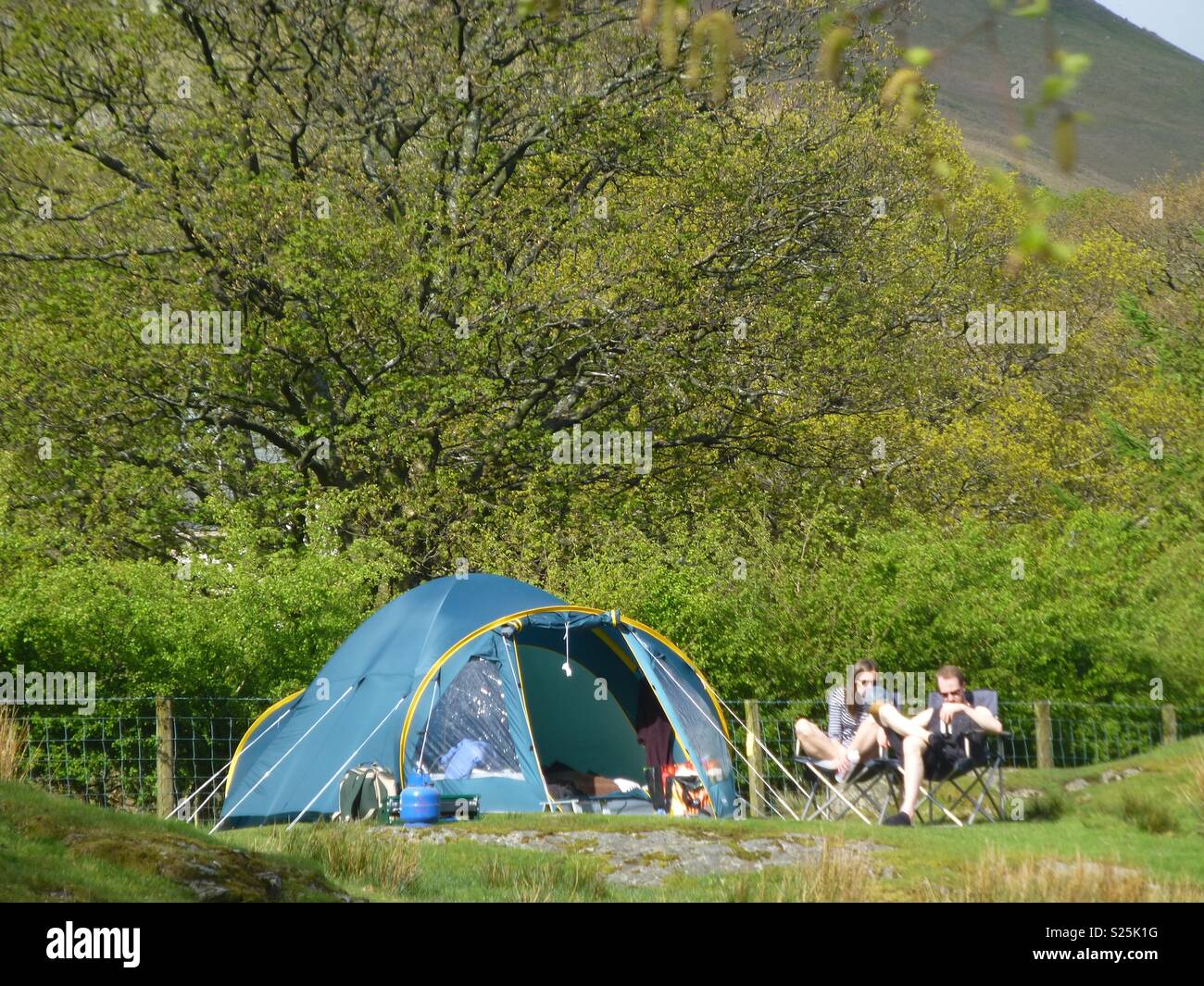 A young millennial couple relaxing during a summer camping trip outside ...