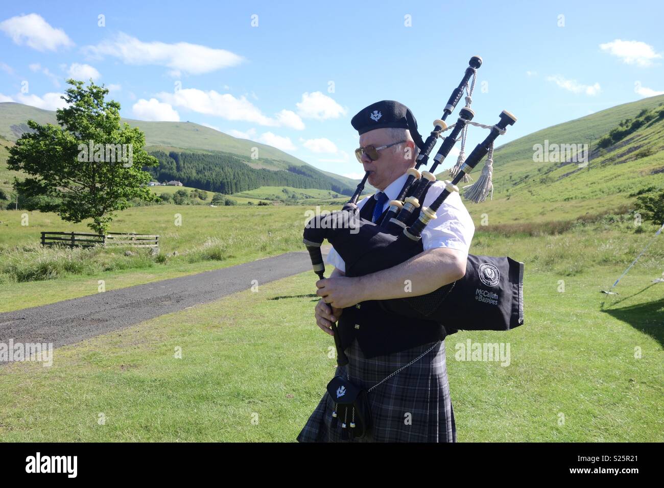 Scottish bagpipe player outside in a valley Stock Photo - Alamy
