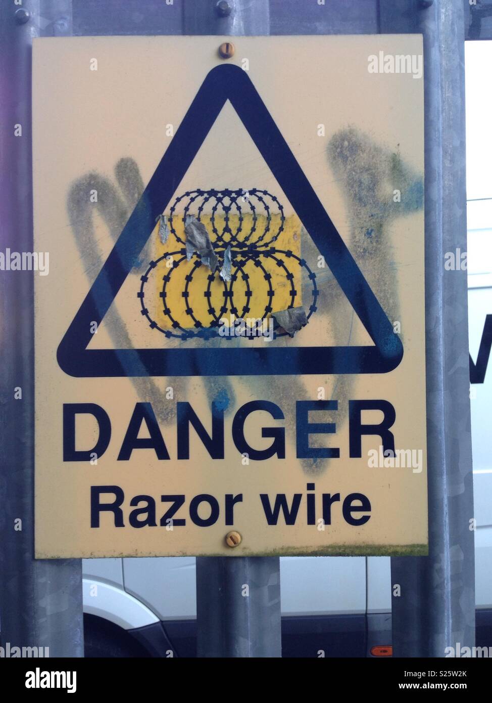 Danger razor wire sign with graffiti Stock Photo - Alamy
