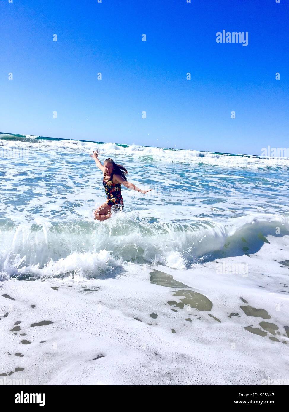 Playing in the waves on the beach in Cali Stock Photo - Alamy