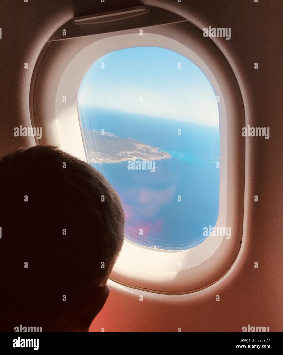 Boy looking out of plane leaving island Stock Photo - Alamy
