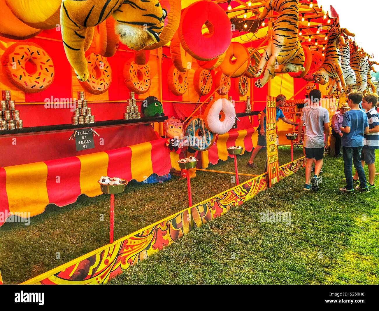 Group of young boys at a coconut shy style of side stall game at the ...