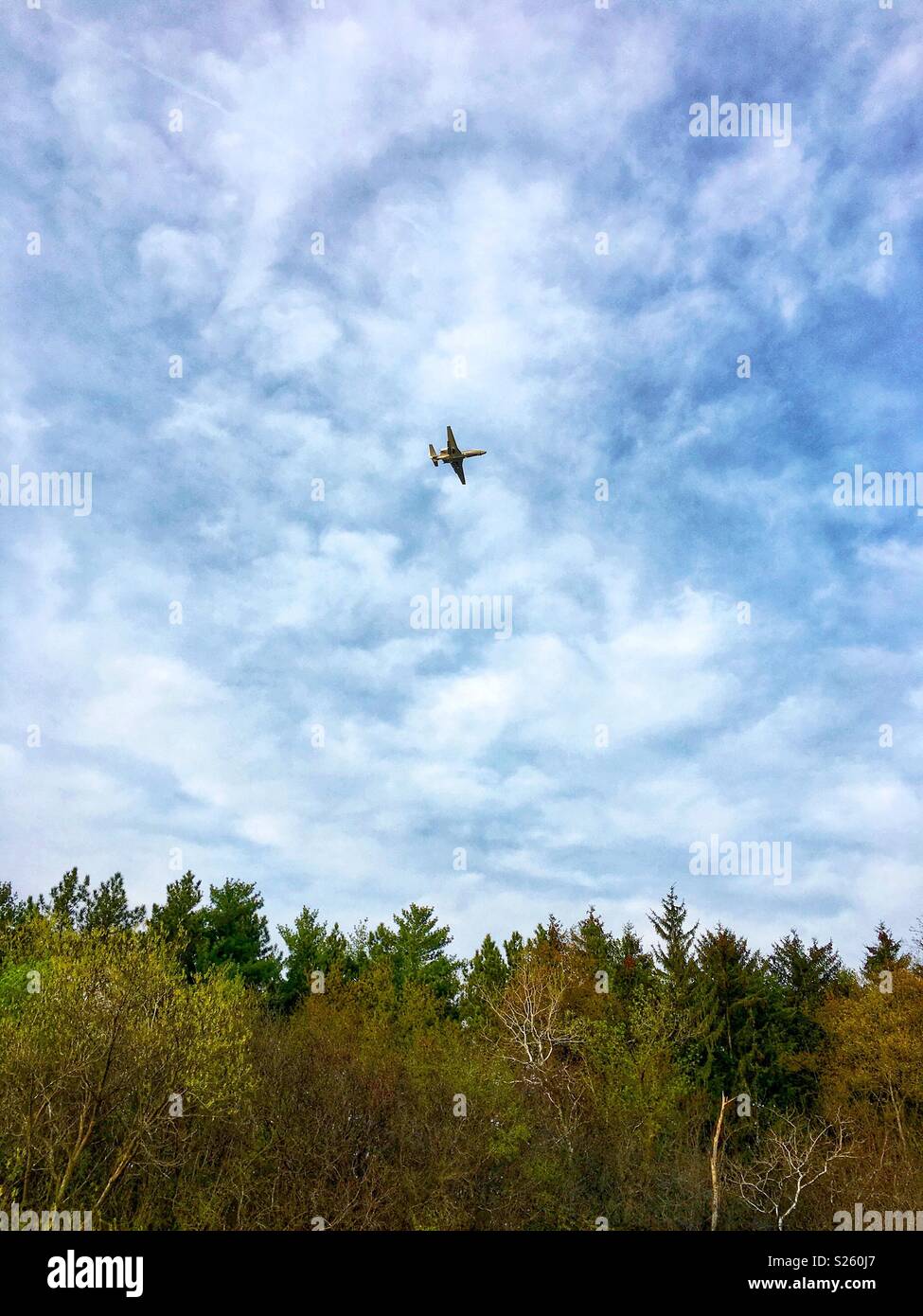 Airplane flying overhead in blue sky with tilted wings hi-res stock ...