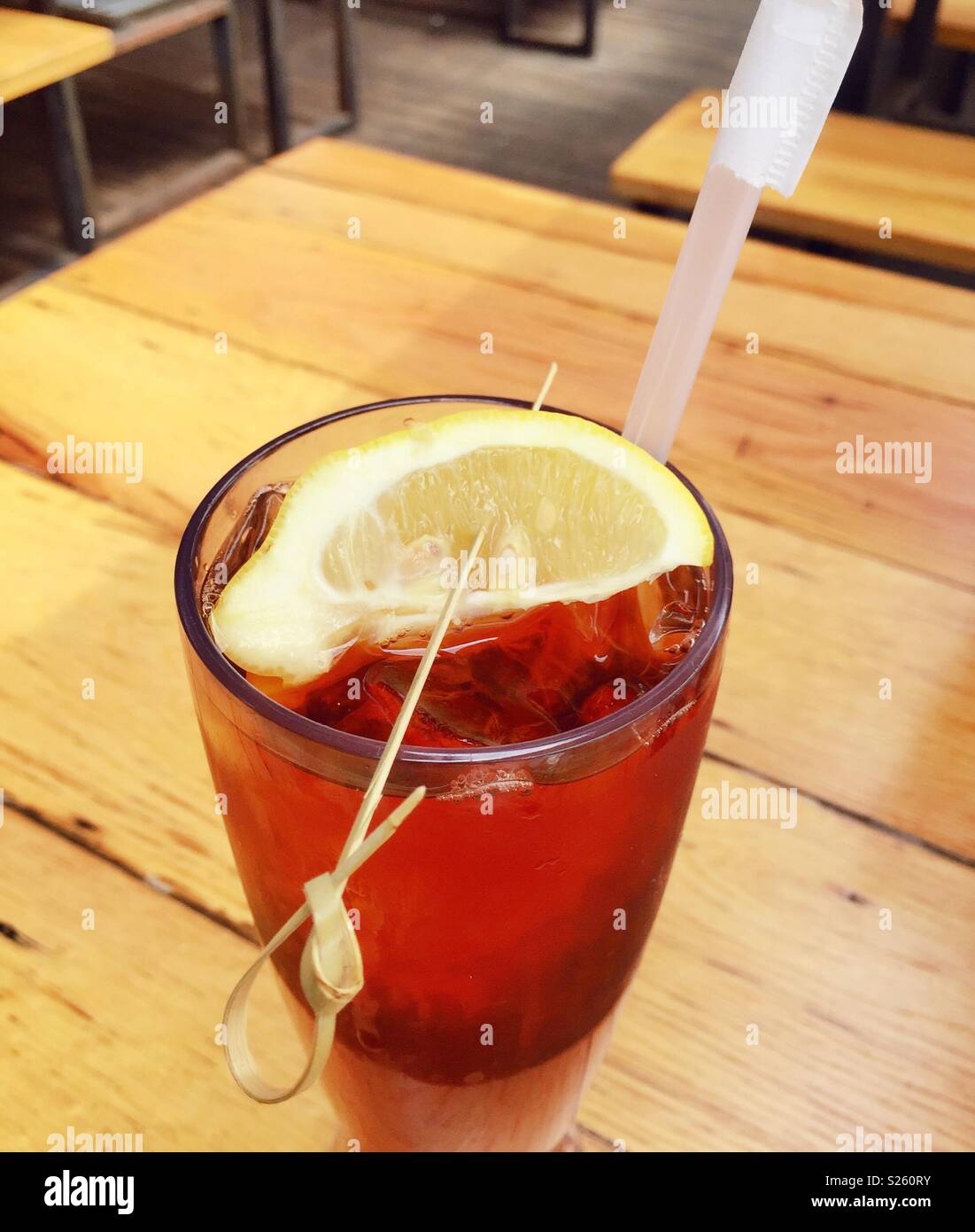 Tall refreshing glass of iced tea with large lemon slice on a outdoor ...