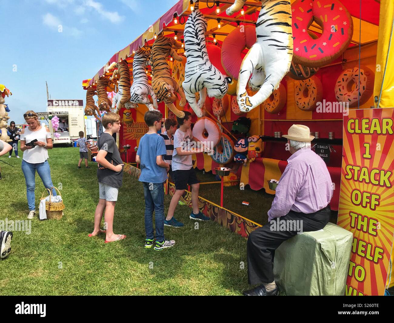 Group of young boys at a coconut shy style of side stall game at the ...
