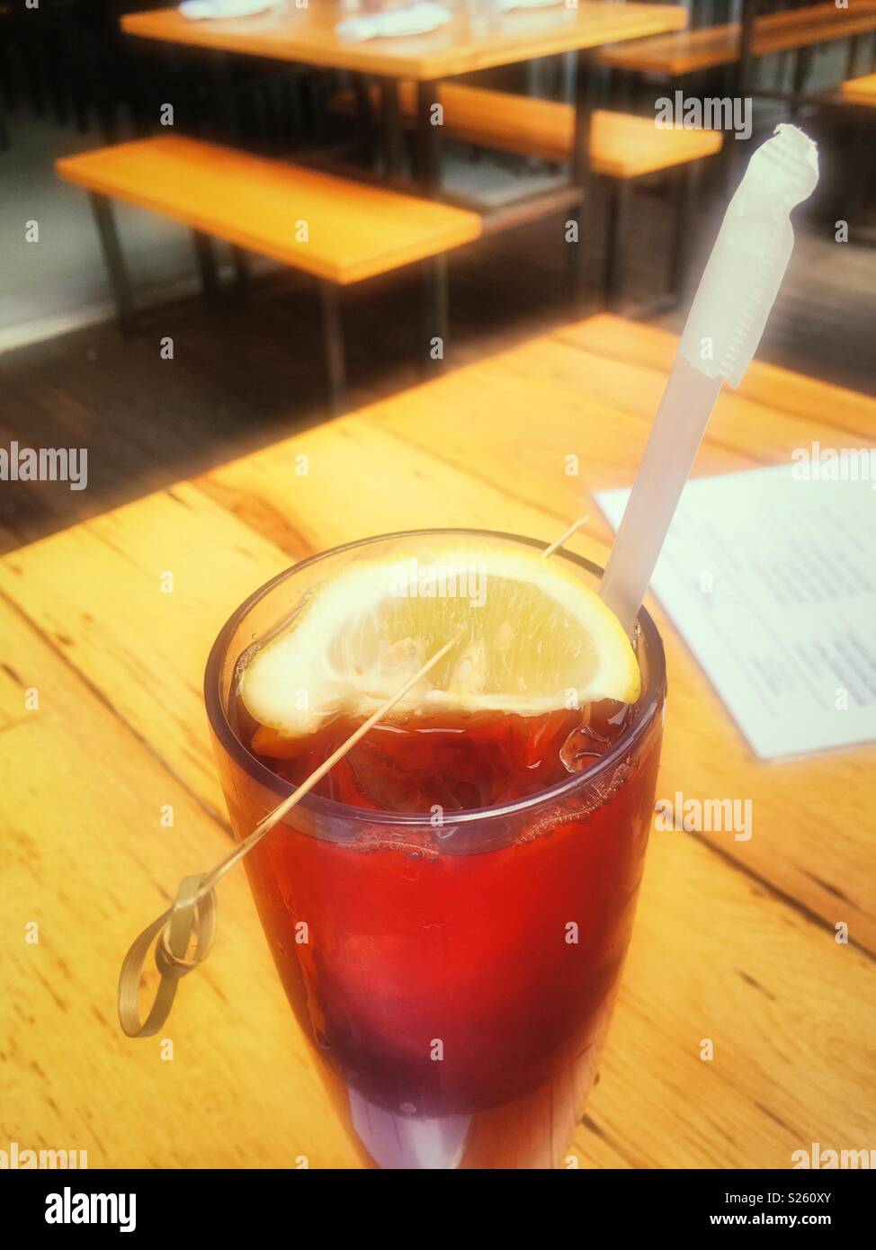 Tall refreshing glass of iced tea with a large lemon slice on an ...