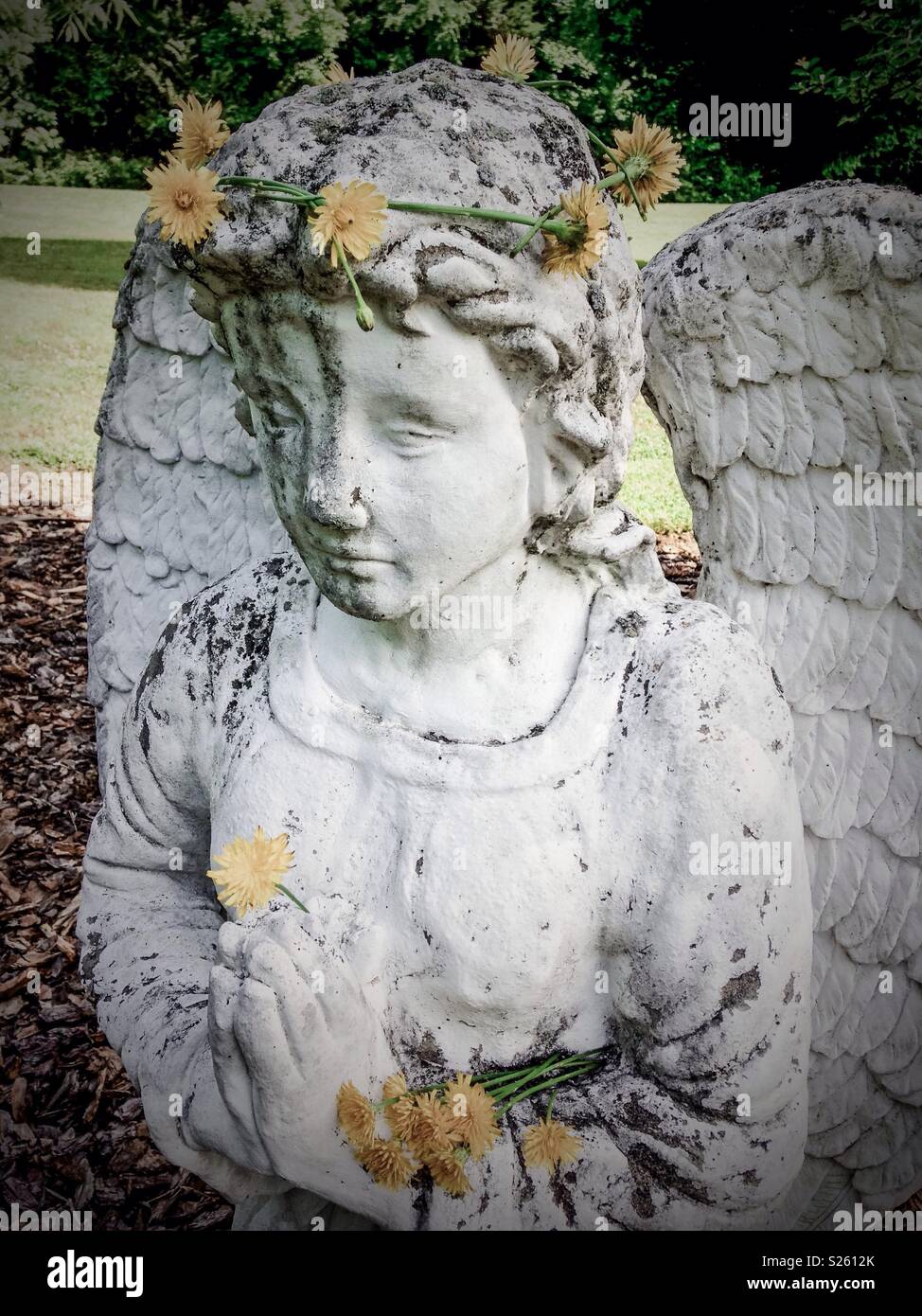 Childlike angel statue with dandelion chain crown Stock Photo - Alamy