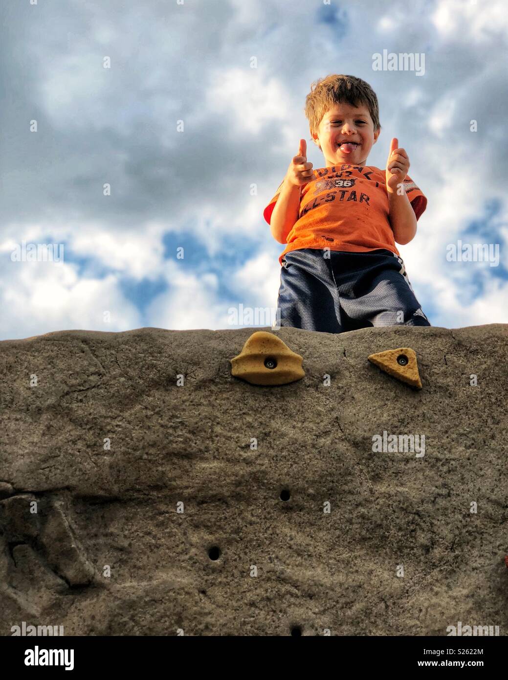 Little boy at rock climbing ledge giving thumbs up Stock Photo - Alamy