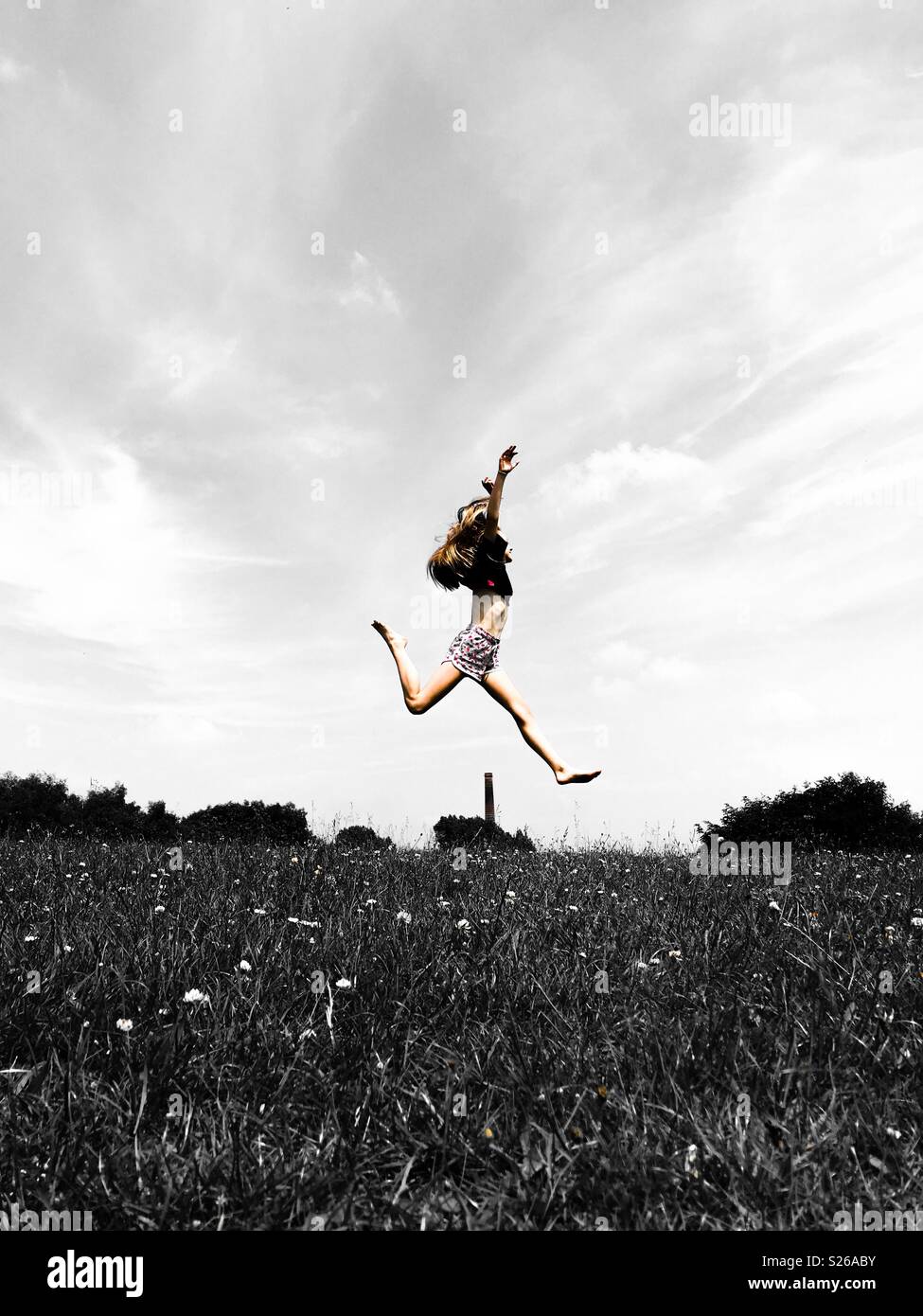Girl leaping in a field Stock Photo - Alamy