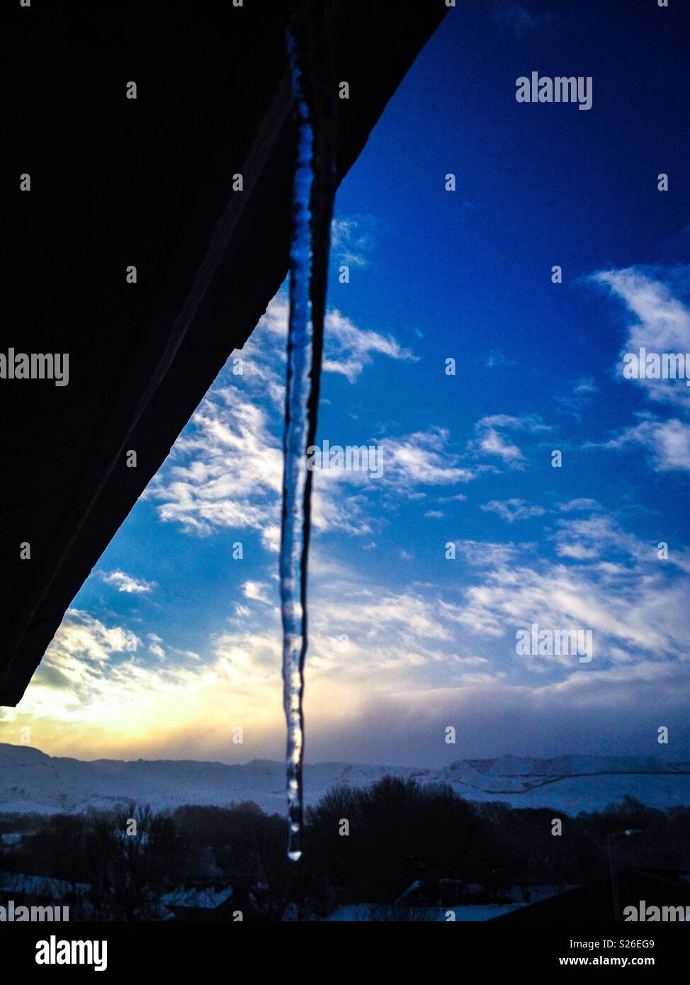 Winter sky with large icicle Stock Photo - Alamy