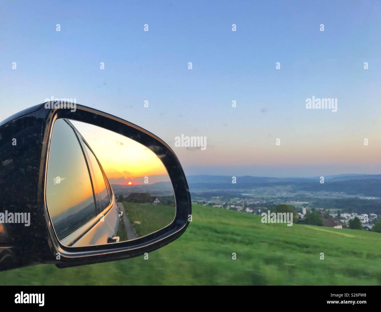Sunset in the rear view mirror Stock Photo - Alamy