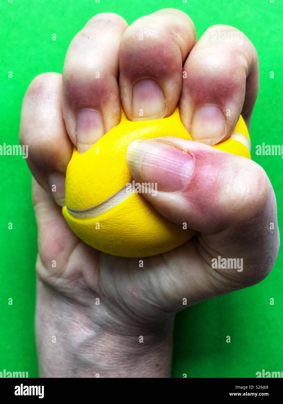 Stress ball in a woman’s clenched fist, against a green background ...