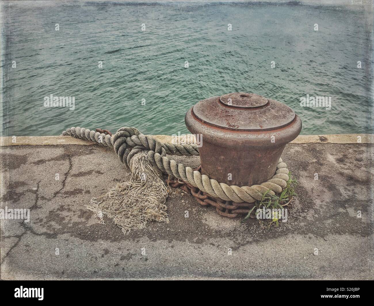 Mooring bollard with weathered rope Stock Photo - Alamy