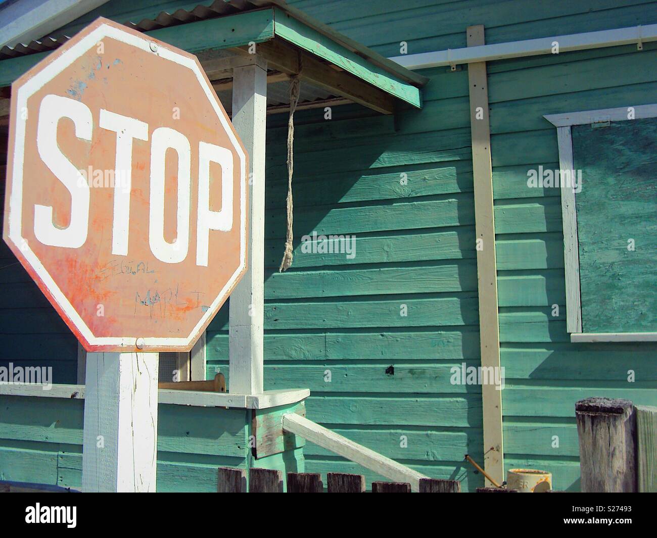 Faded stop sign with pastel colored weathered house in background Stock ...