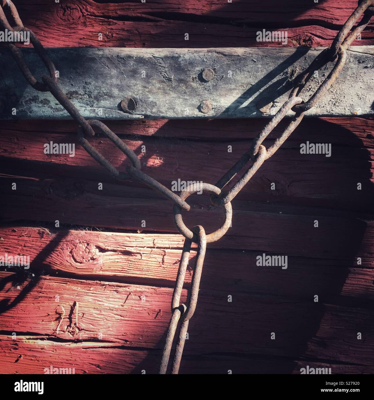 Rusty chains with red painted timber wall as a background. Rusty ring ...
