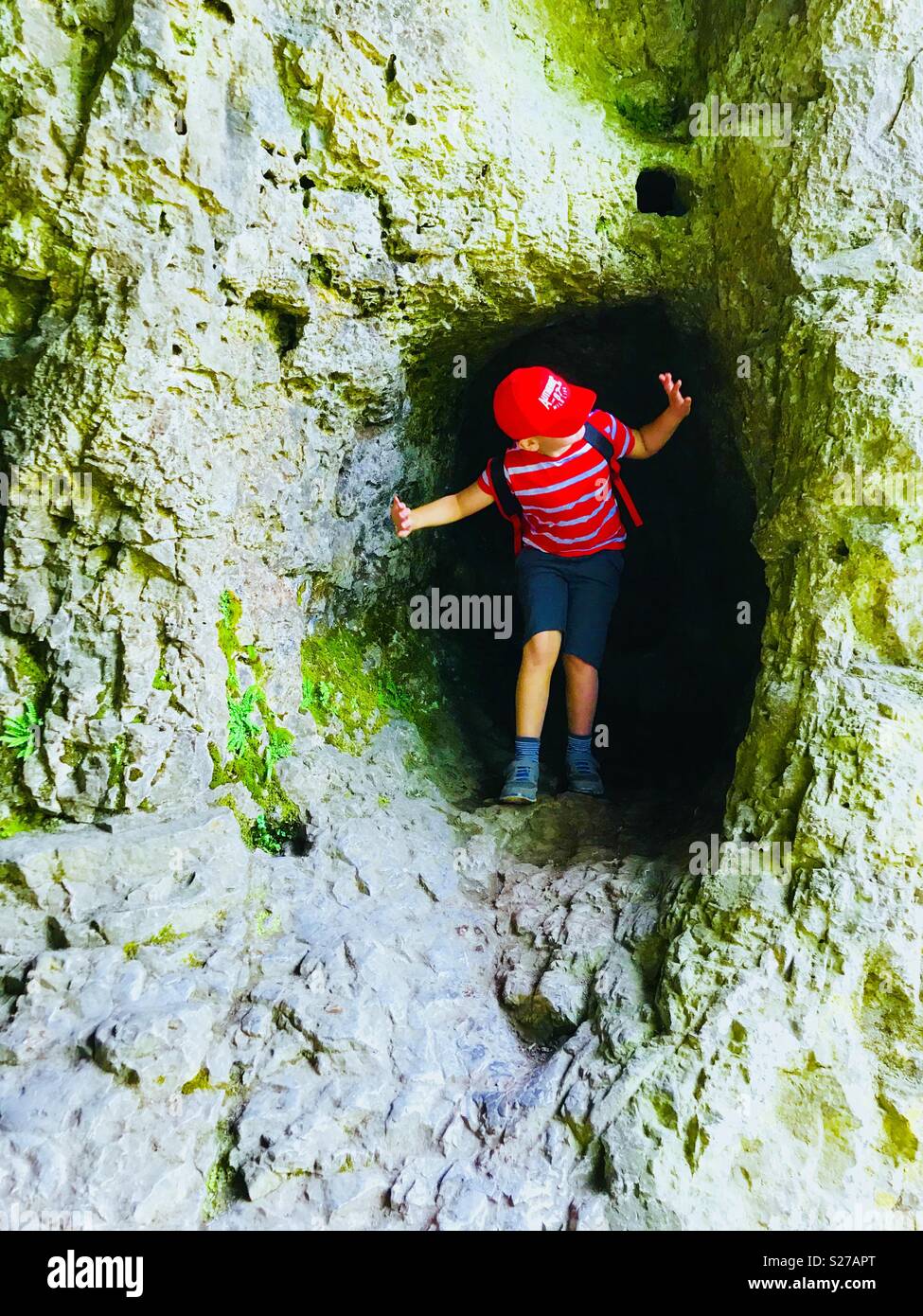 Boy emerging from cave Stock Photo - Alamy