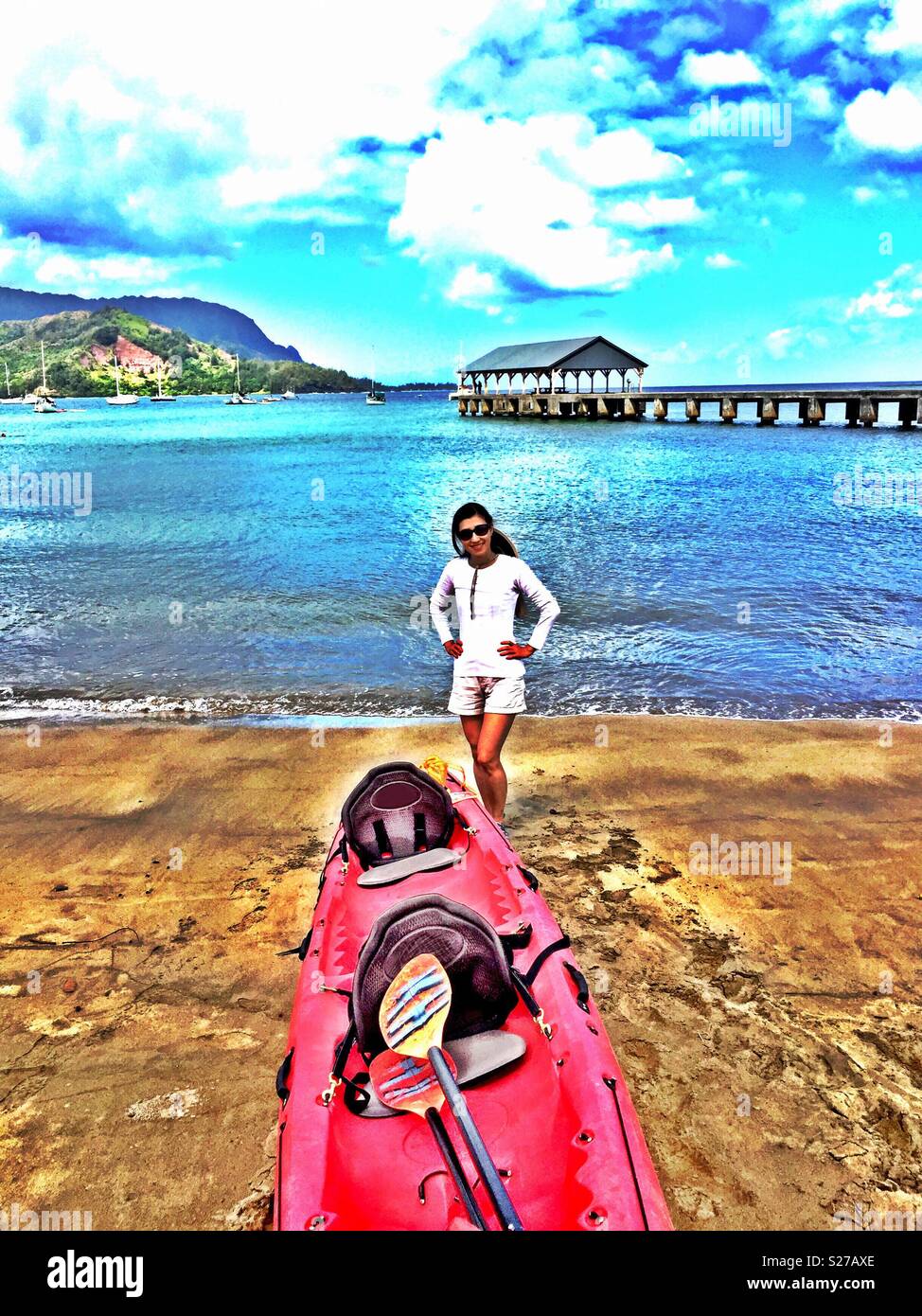 Athletic young woman poses proudly in front of her beached kayak on ...