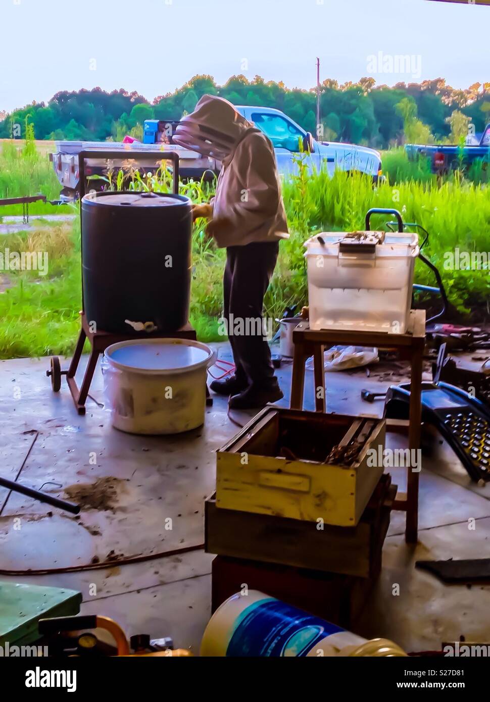 Blurred photo of beekeeper extracting honey in homemade extractor. View ...
