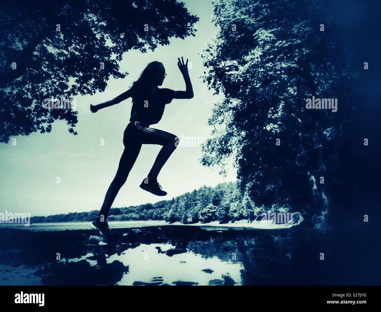 Girl in silhouette running and jumping over stream Stock Photo - Alamy