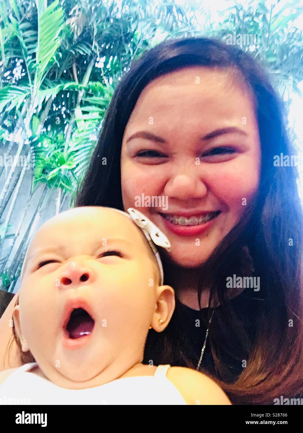 Yawning baby with mommy Stock Photo - Alamy