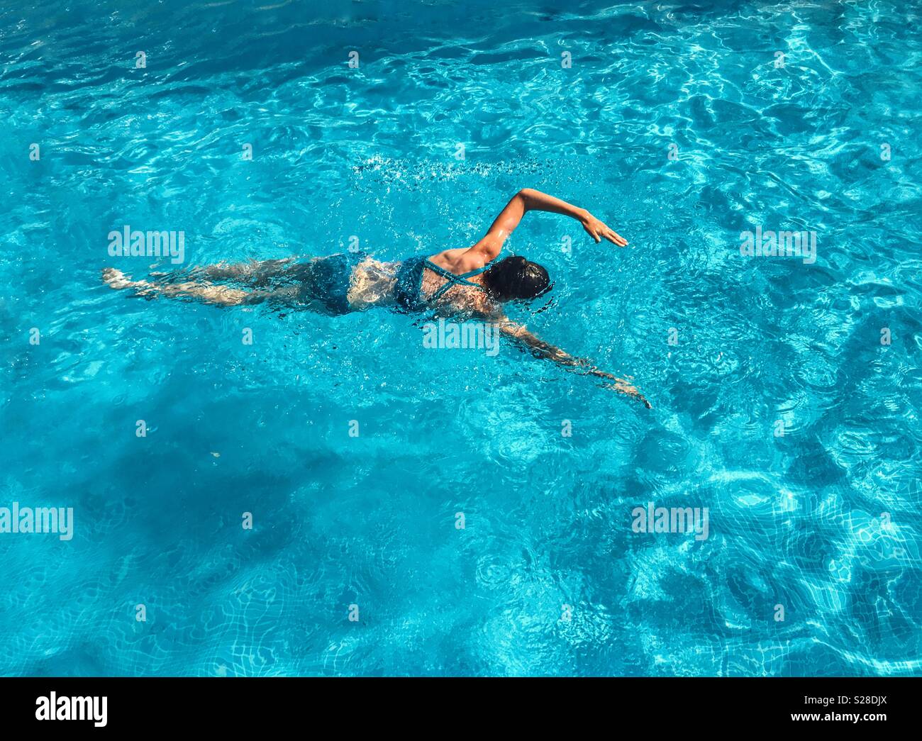 Girl in blue swimming costume swimming front crawl in blue pool Stock ...