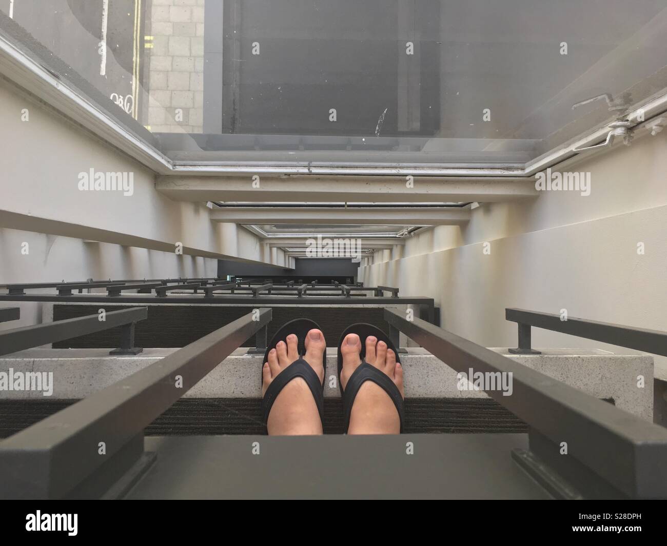 Feet hanging over edge of stairwell Stock Photo - Alamy