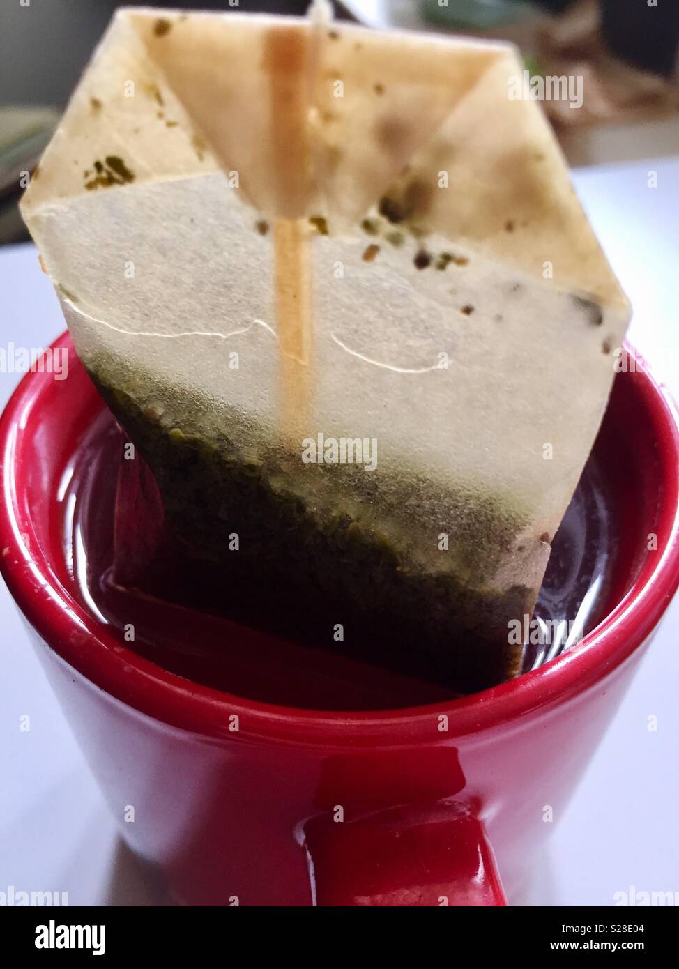 Removing a tea bag from a red mug with hot water Stock Photo - Alamy