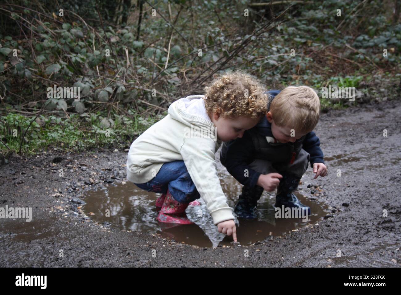 Girl & boy siblings playing in a muddle puddle Stock Photo - Alamy