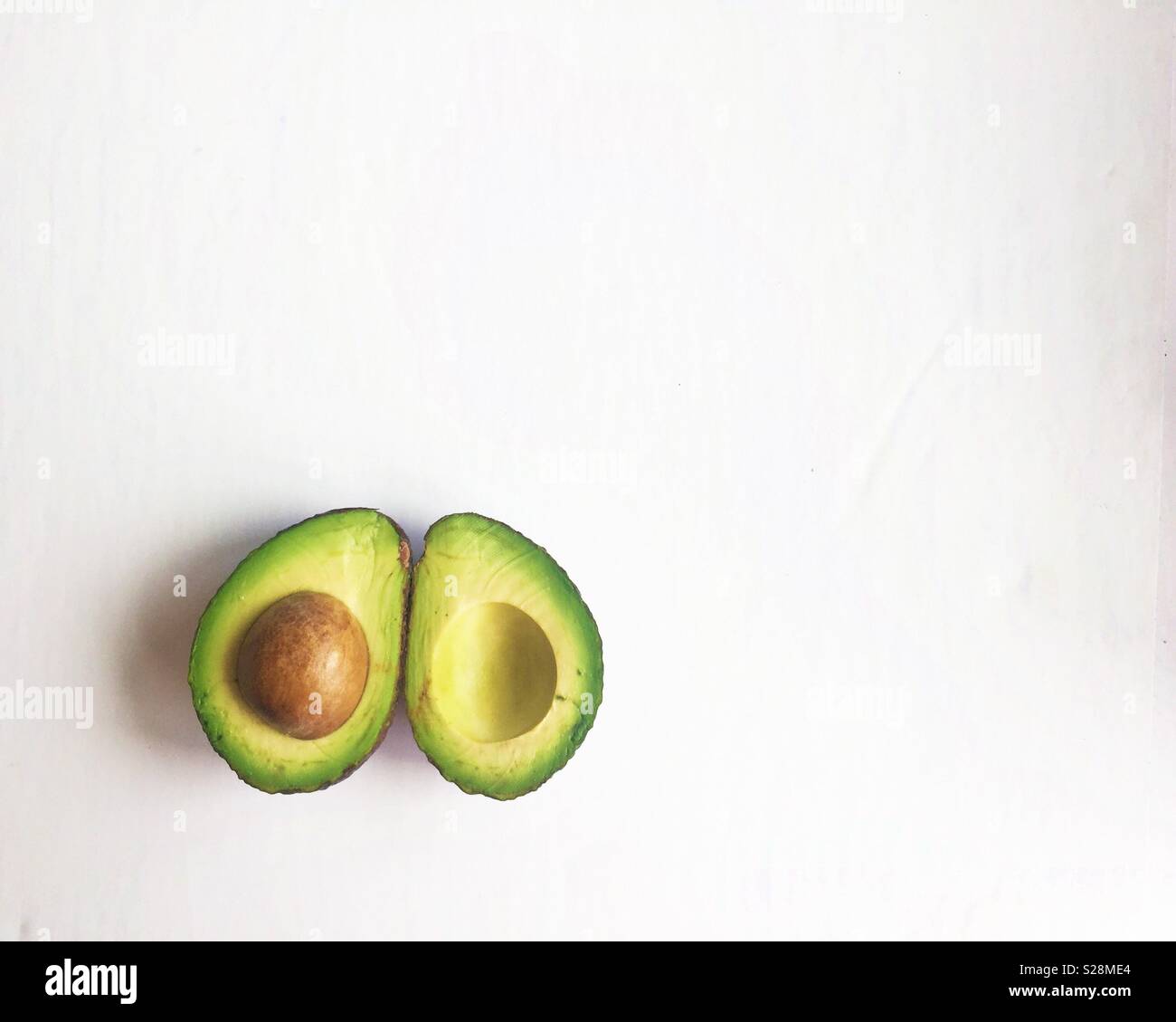Avocado split in half on a white background Stock Photo - Alamy