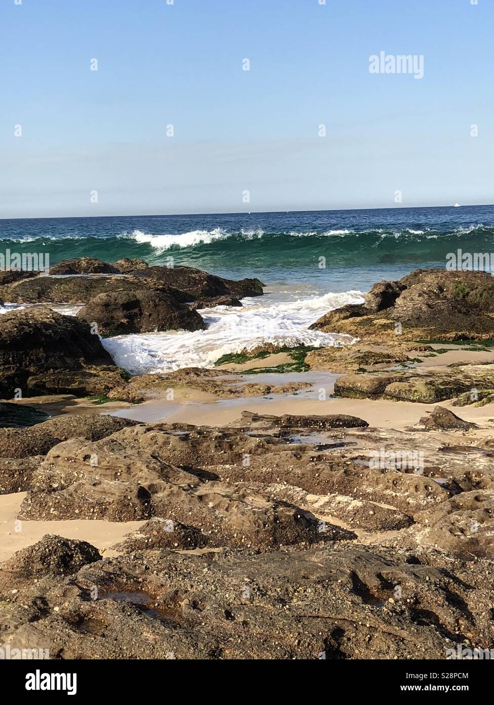 Wave coming in towards the rocks Stock Photo - Alamy