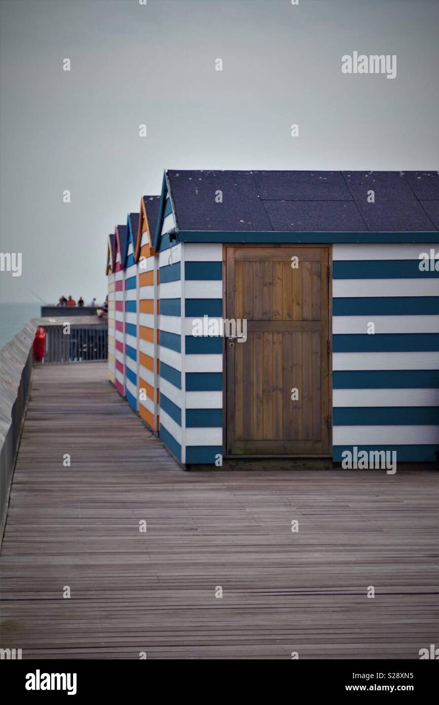 Striped colourful beach huts on pier Stock Photo - Alamy