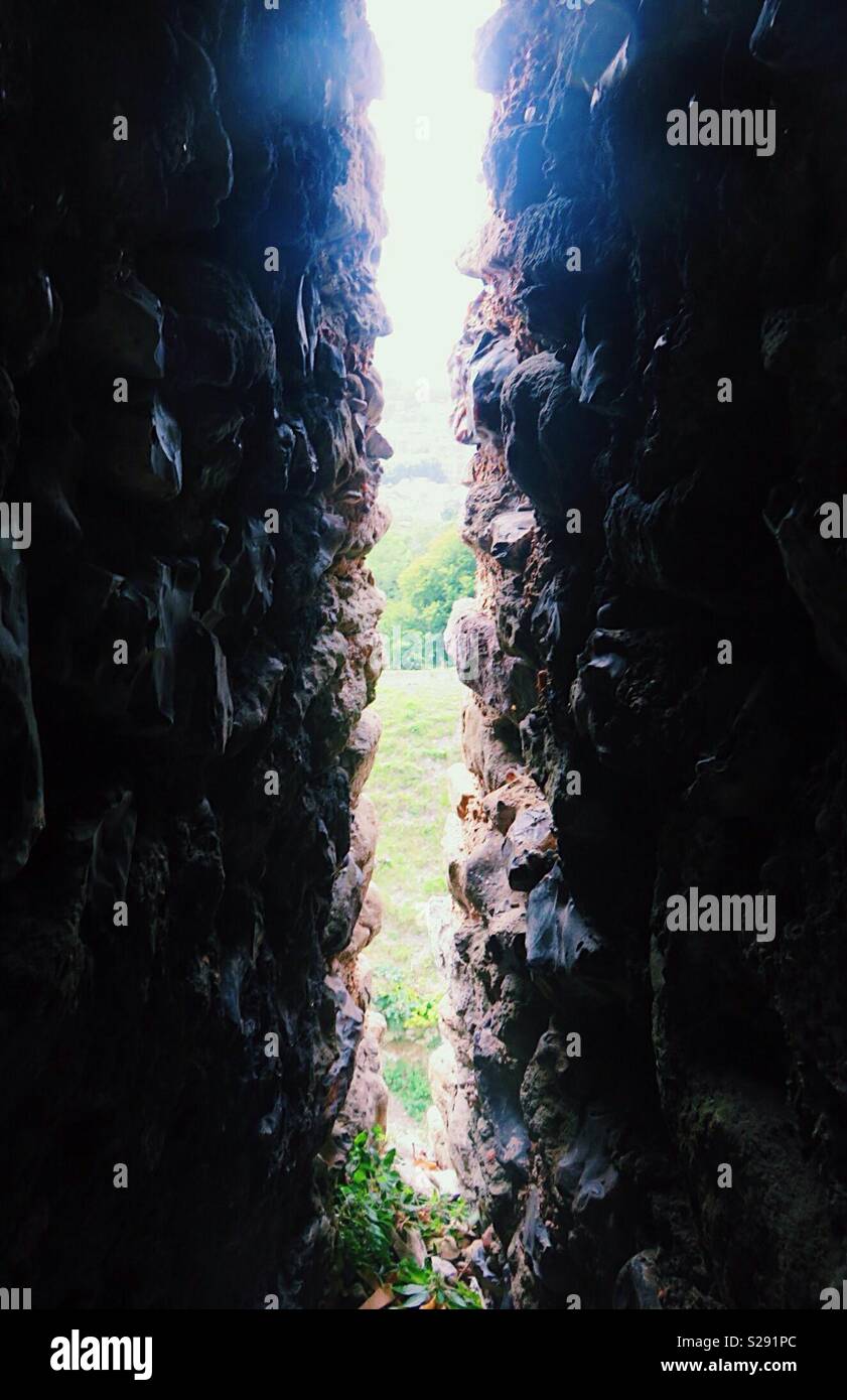 Gap through rock wall leads to green fields Stock Photo - Alamy