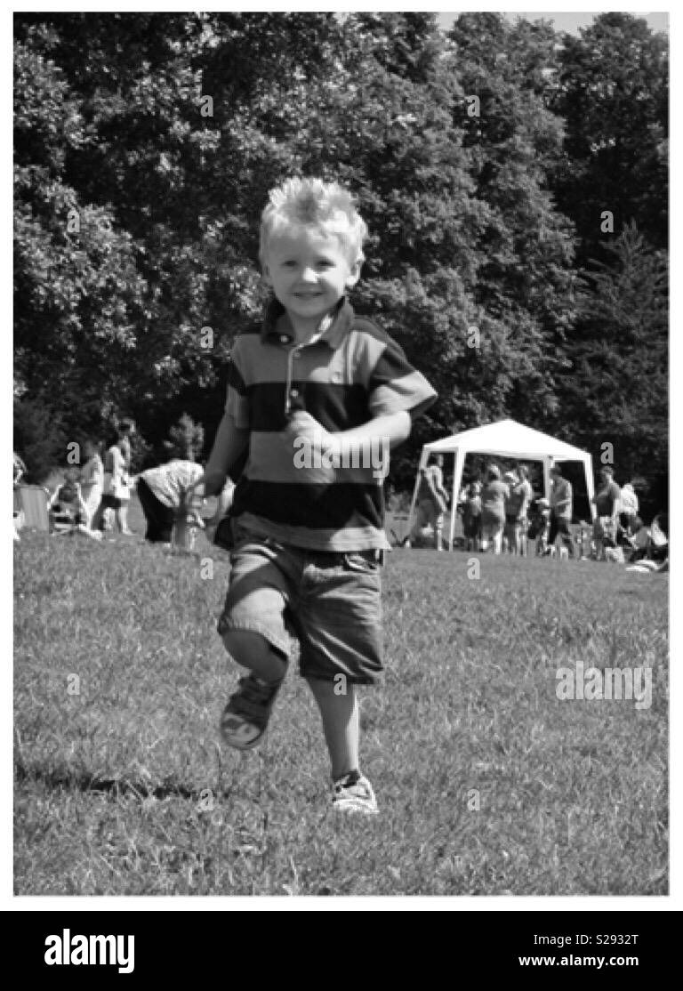 Little boy running around a park on the grass Stock Photo - Alamy