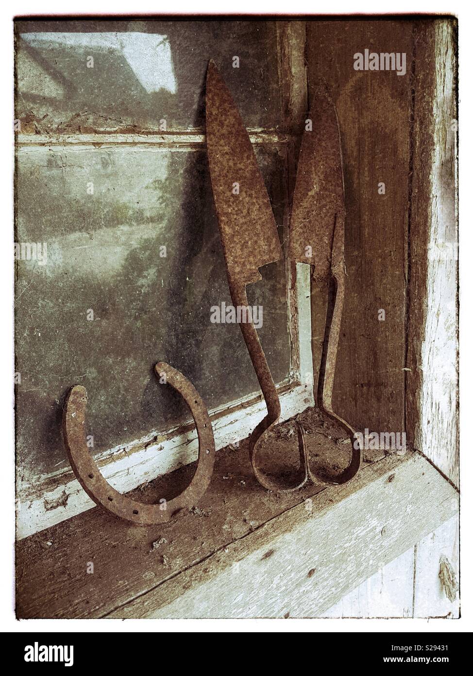 Rusty horseshoe and shearing clippers left on a dusty, old windowsill ...