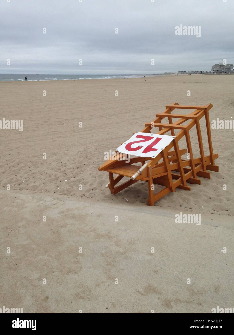 A wood lifeguard chair laying sideways in the sand on the beach at the ...