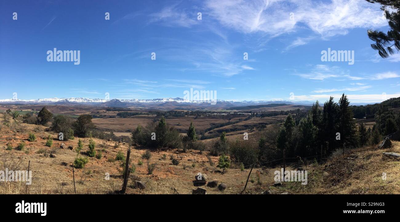 Snow capped drakensberg mountain landscape with green pastures in ...