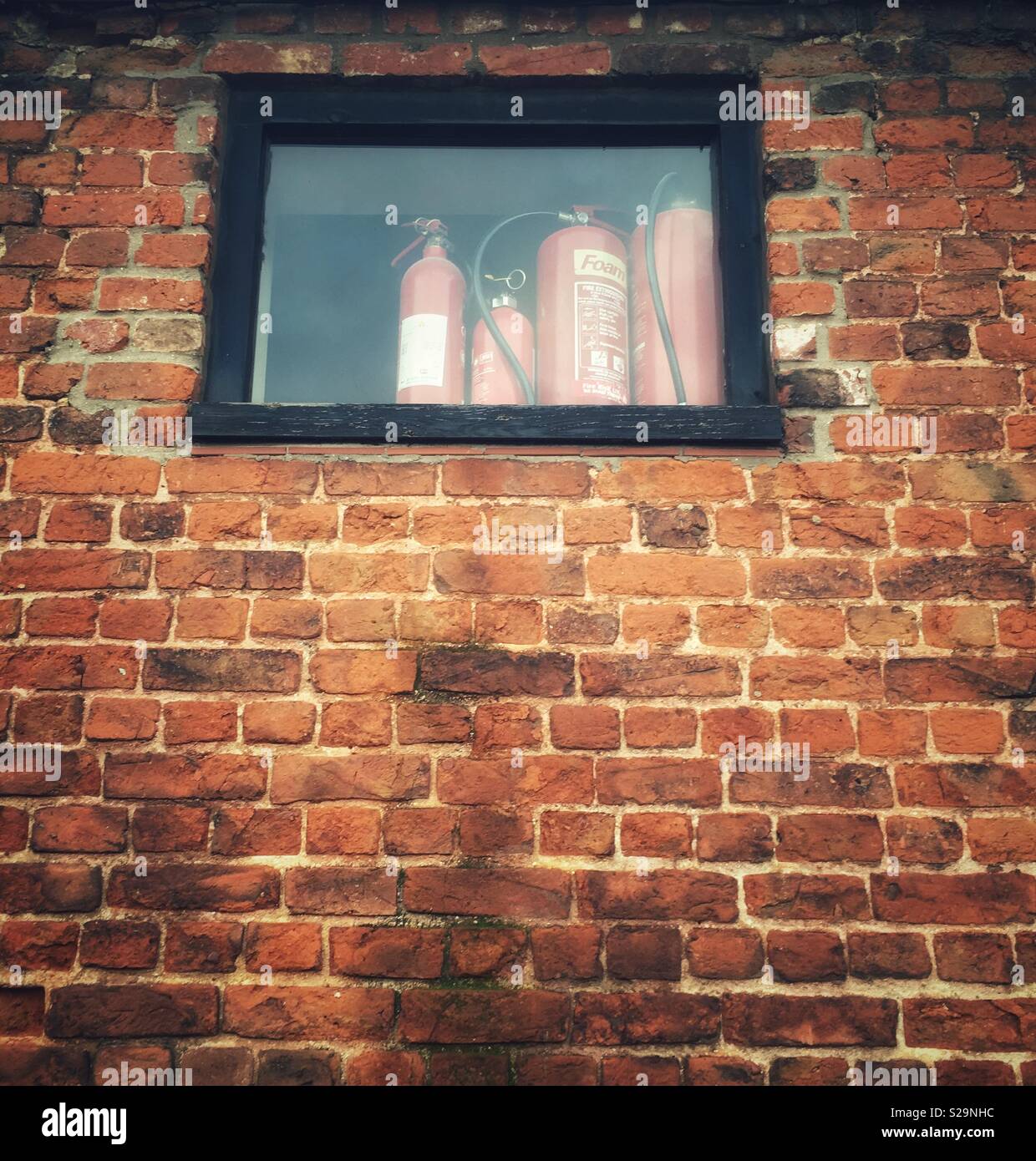 Fire extinguishers in window of a brick building Stock Photo - Alamy