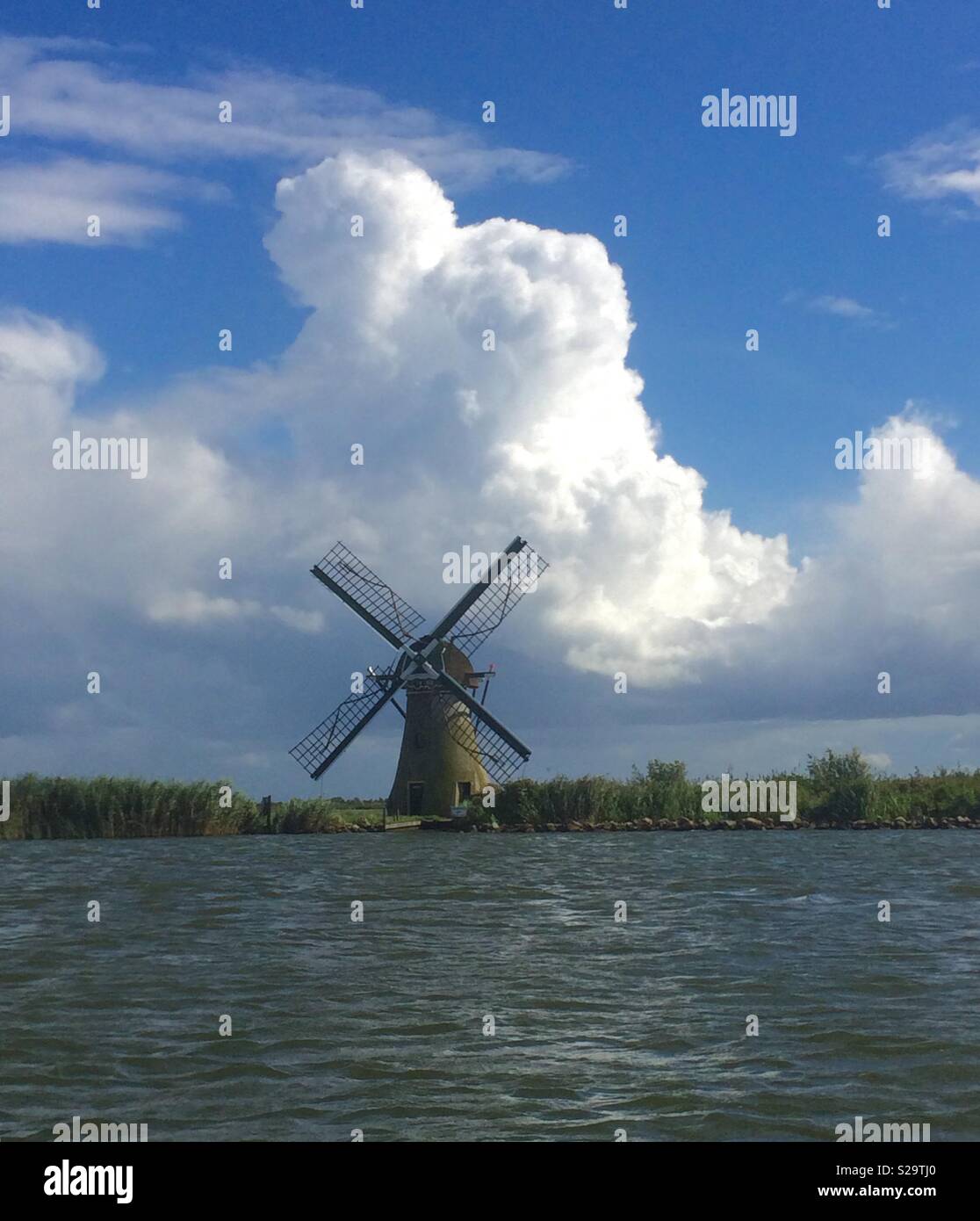 Dutch windmill on water with white clouds Stock Photo - Alamy