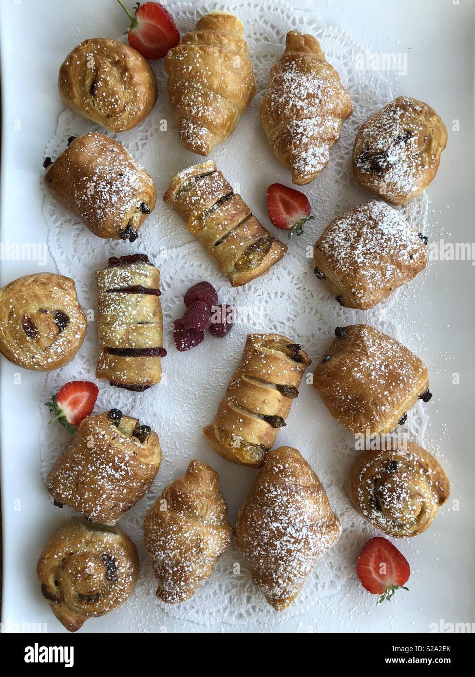Selection of hot pastries on a white platter with fruit garnish Stock ...