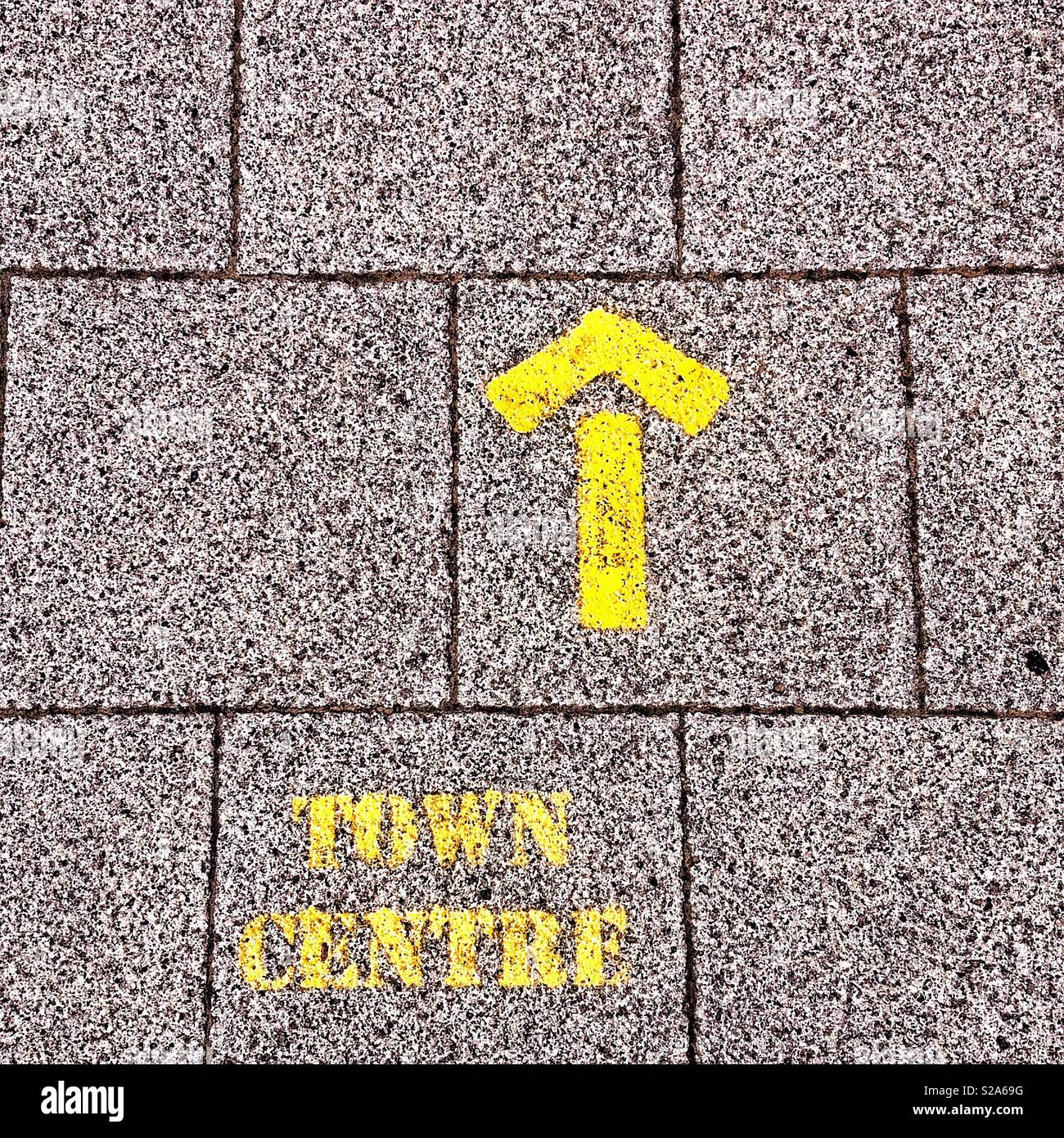 A sign showing the direction to the town centre painted on a pavement ...