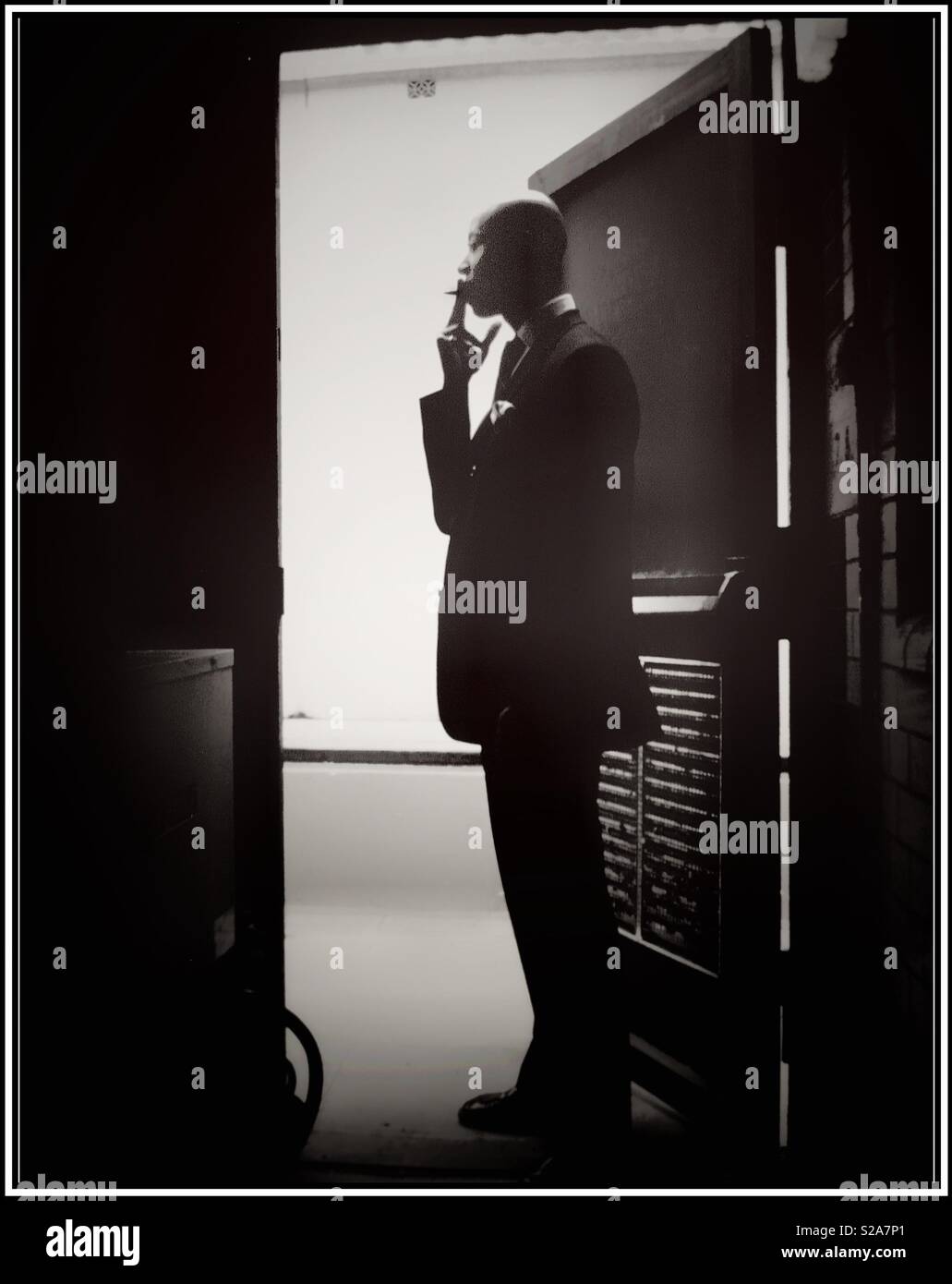 A dapper black gentleman smoking a cigarette in a doorway Stock Photo ...