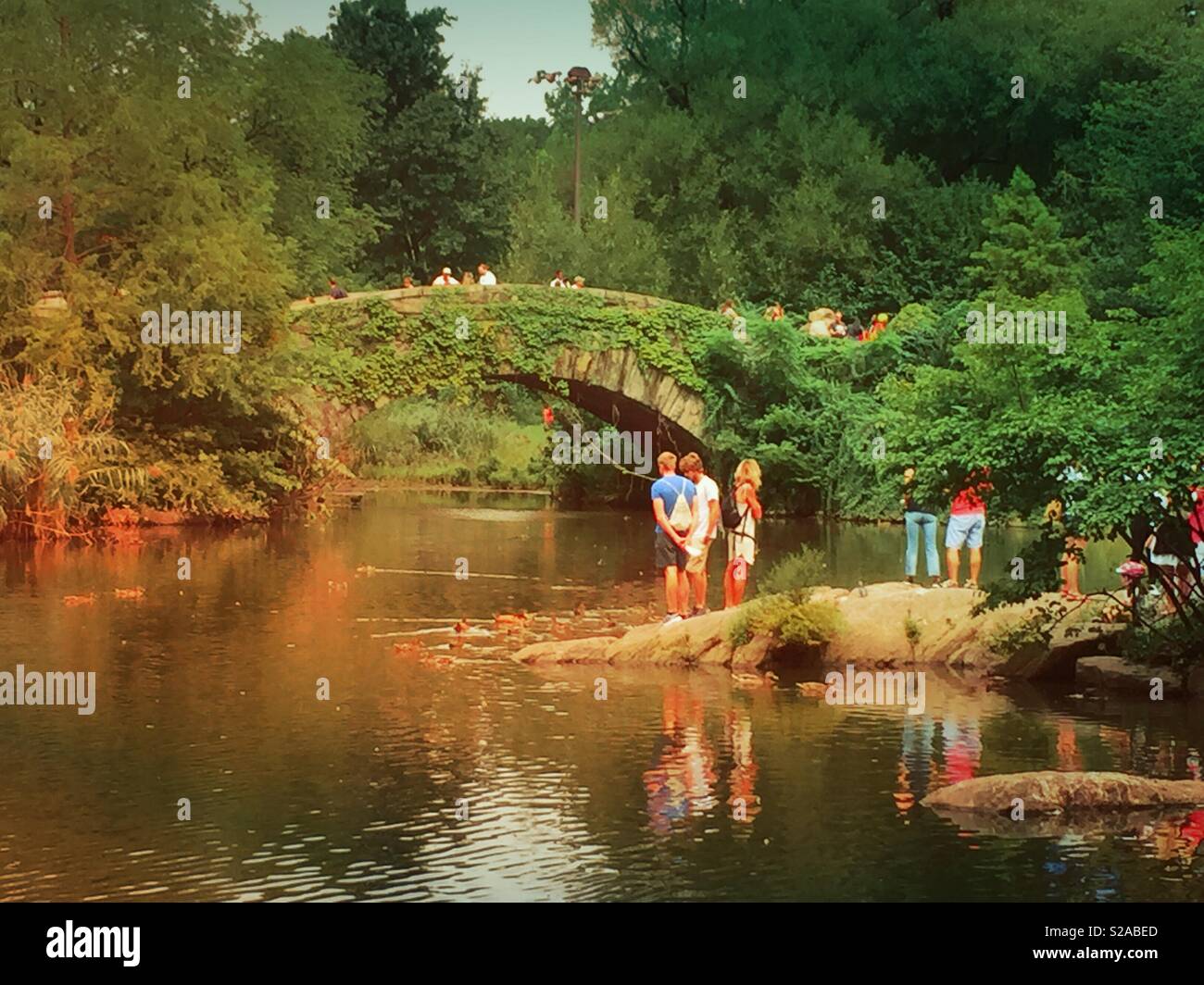 Tourists gather at the pond in front of Gapstow Bridge, Central Park ...