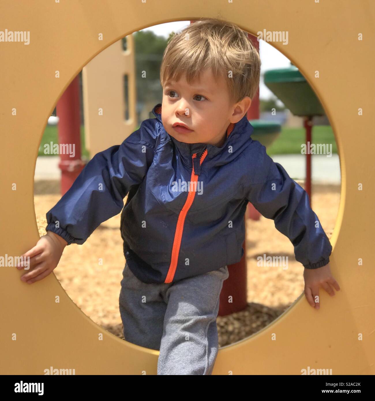 Toddler boy playing at playground, climbing through play structure ...