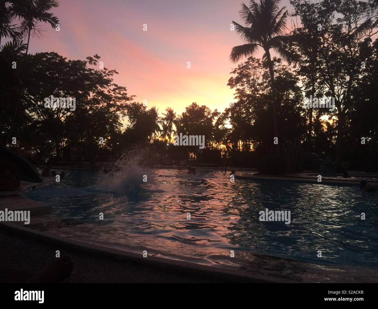 People splashing in the pool at sunset Stock Photo - Alamy