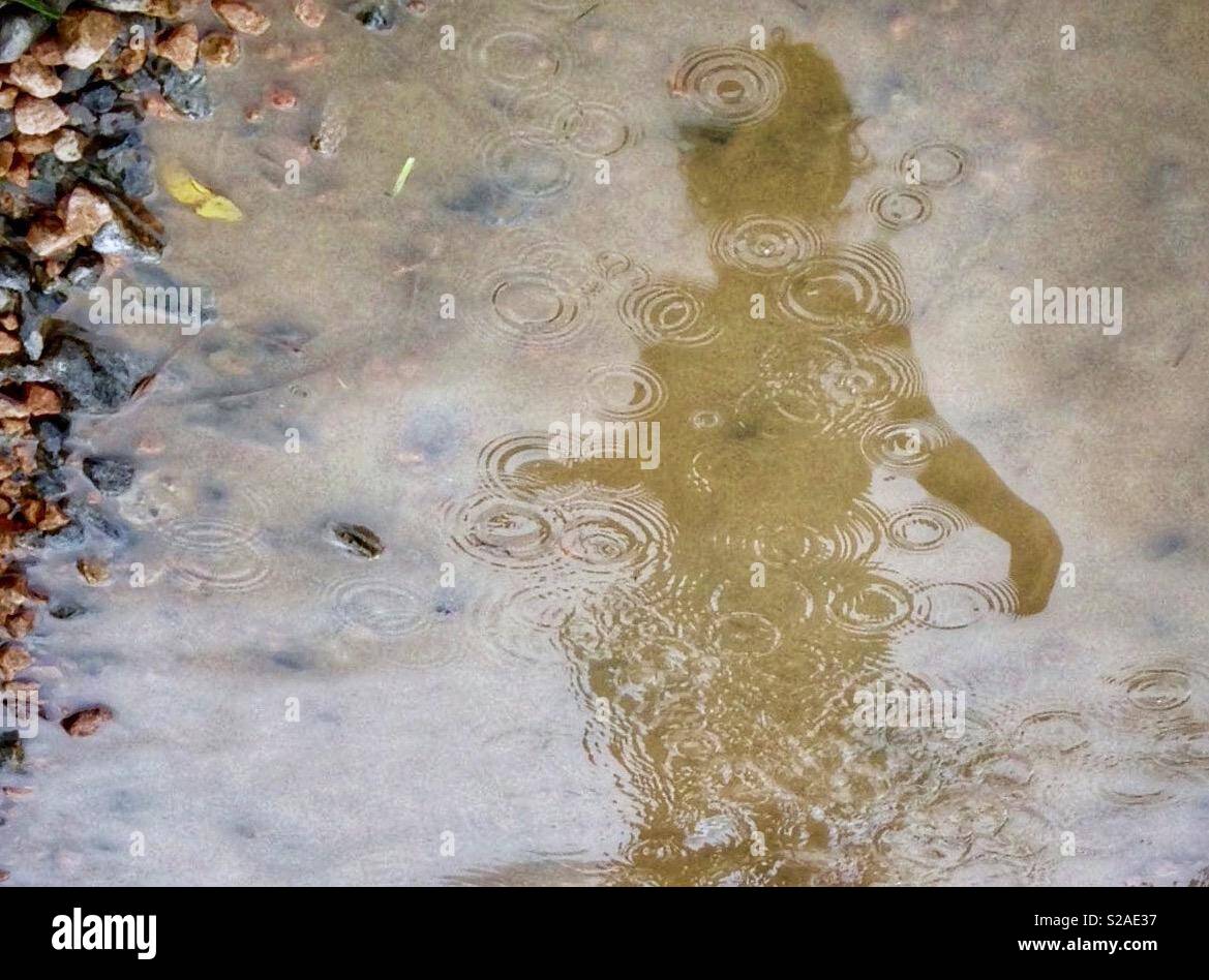 Toddler's reflection in puddle- with ripples on the surface Stock Photo ...