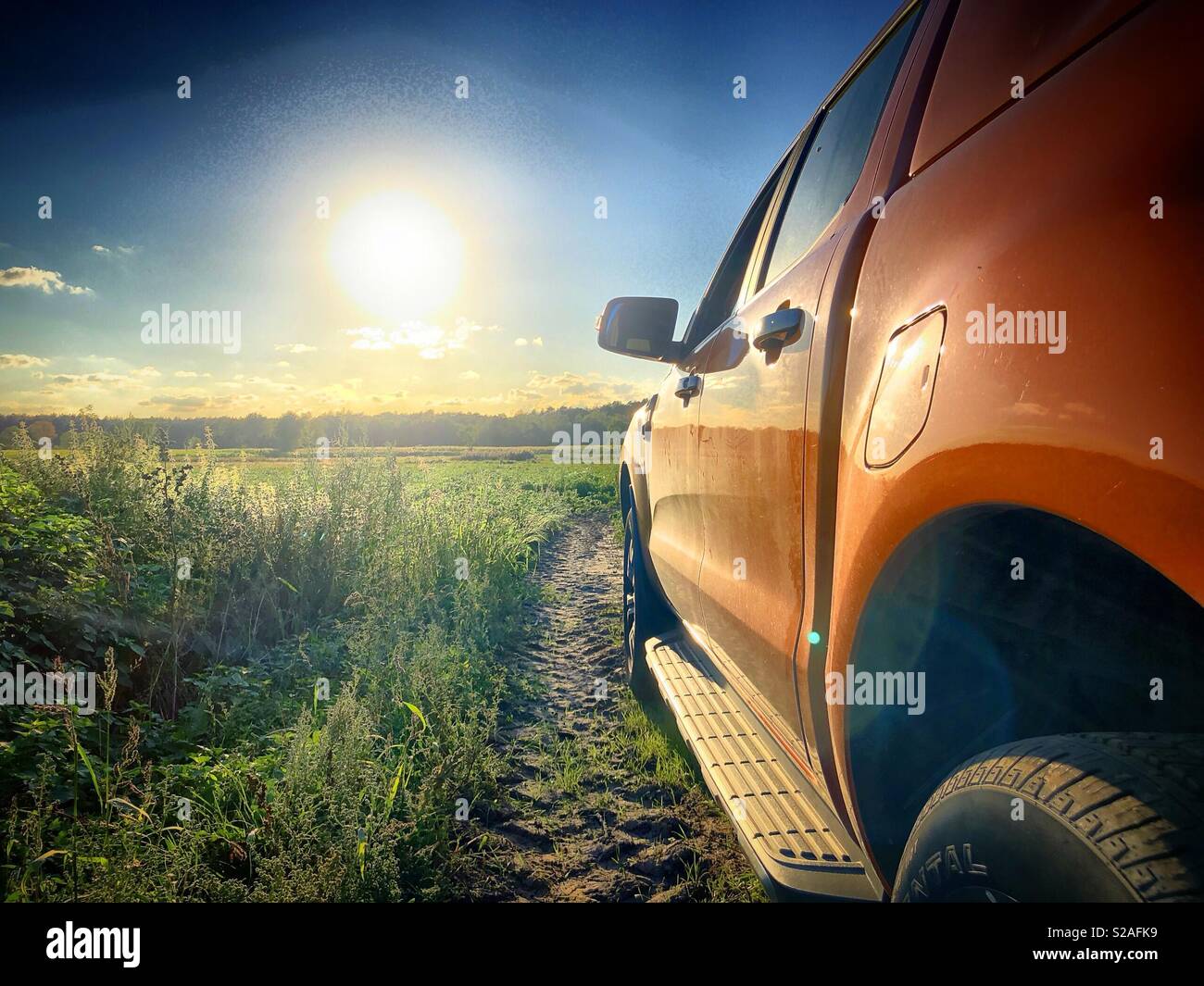 A 4x4 pickup truck in an rural off road path against a sunset Stock ...
