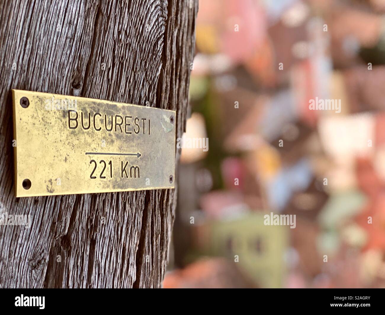 City direction and distance indicator on a wood post with blurred city ...